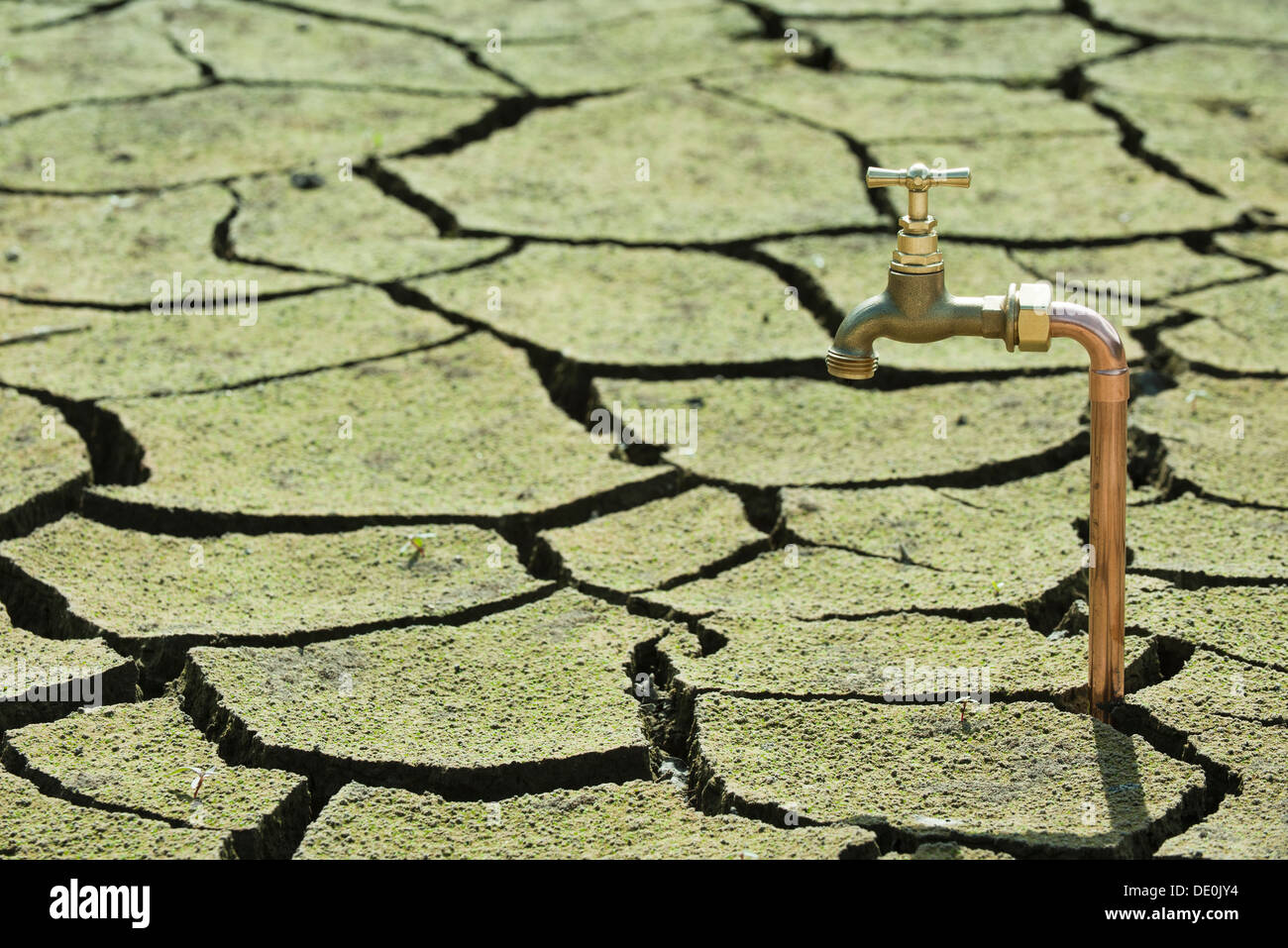 Faucet emerging from dry, cracked earth Stock Photo - Alamy