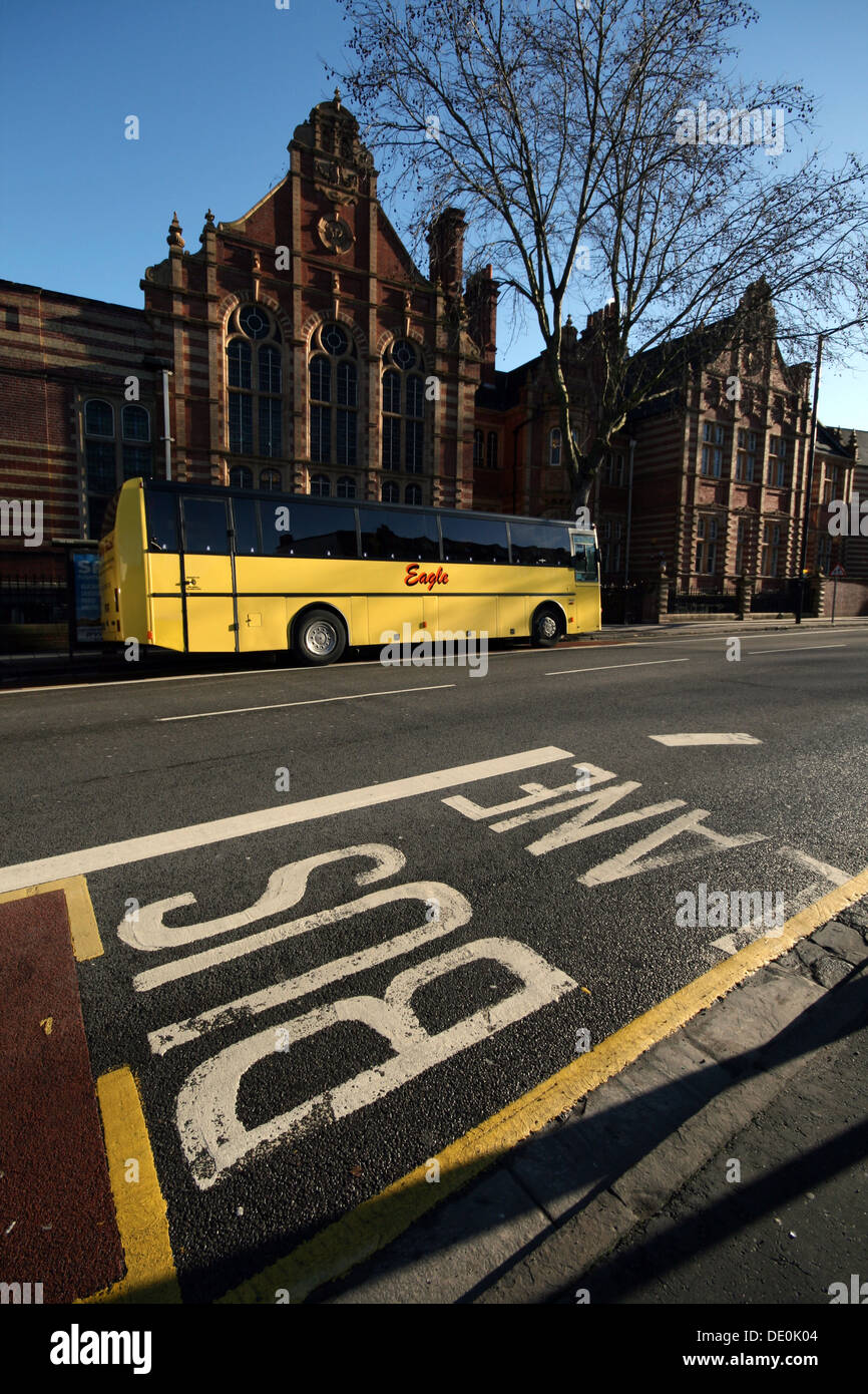 A yellow bus stands opposite a sign saying 'bus lane' Stock Photo - Alamy
