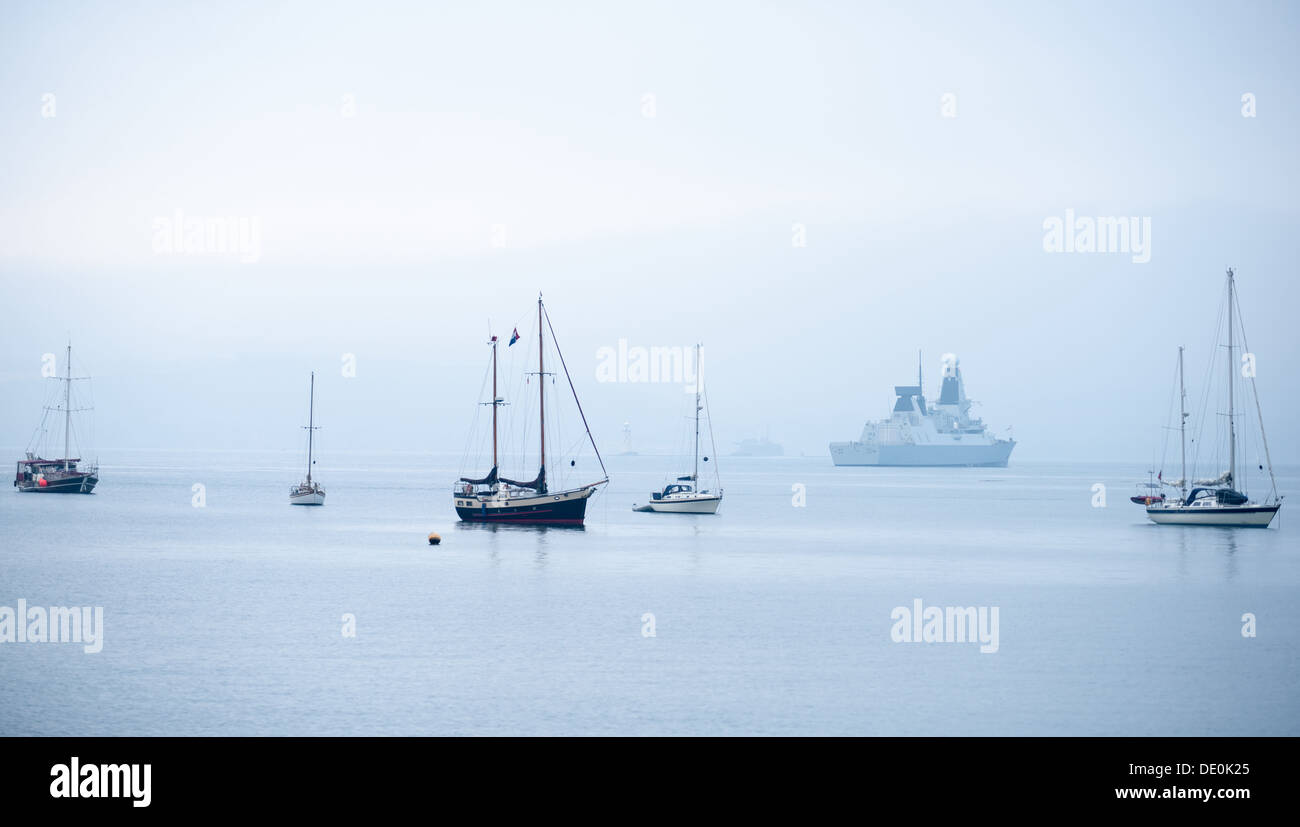 Misty morning light across harbor at Cawsand, England with boats moored ...