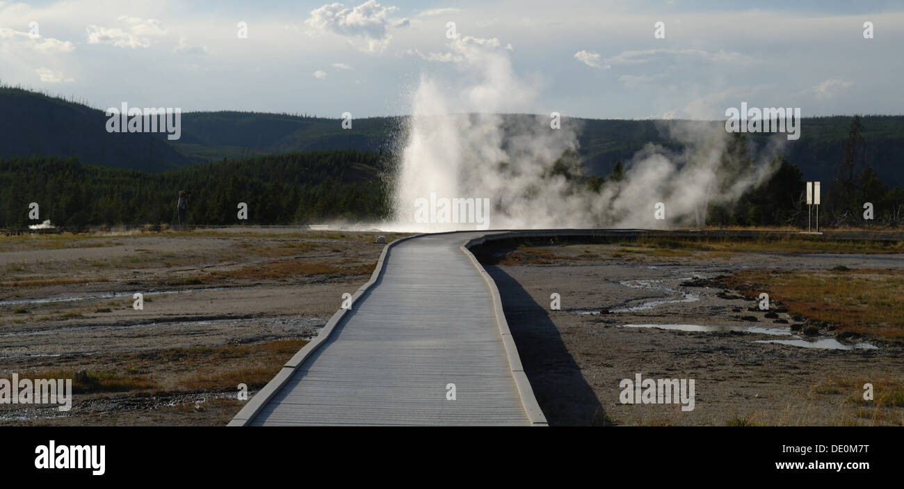 Sunny boardwalk view, towards grey sky hills, steam erupting from ...
