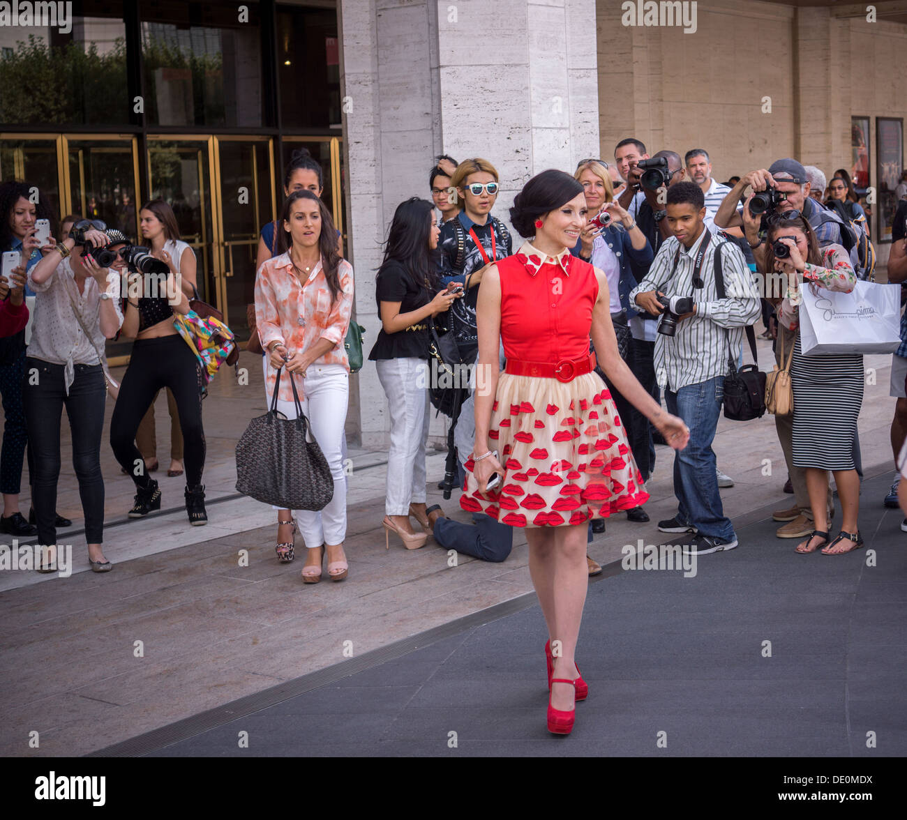 Crowds of fashionistas and photographers create a fashion scene outside ...