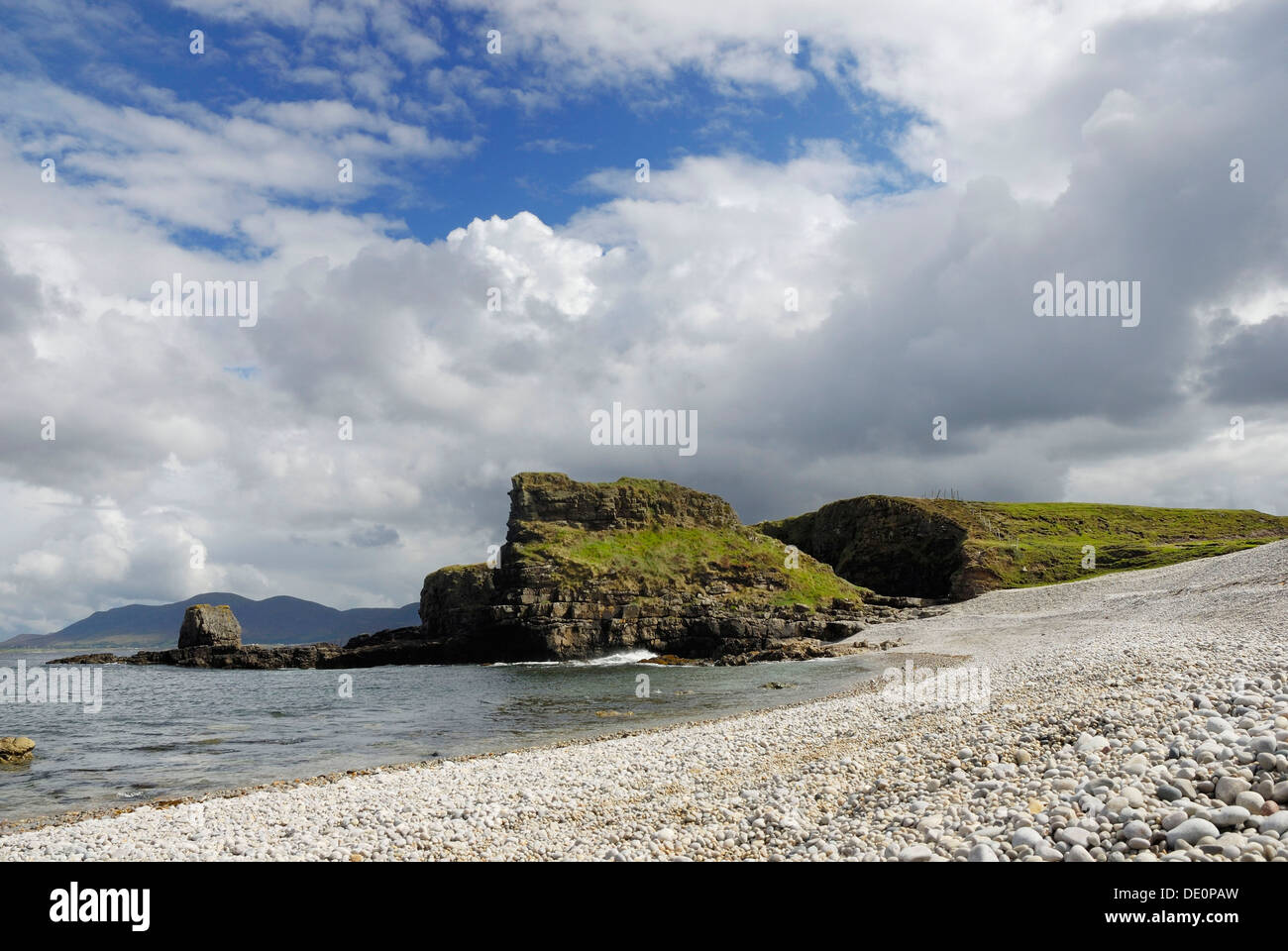 Grass-covered limestone cliffs on a wide pebble beach, County Donegal ...