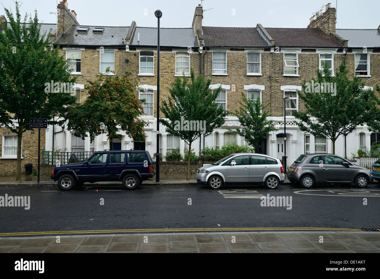 Typical street of London, with brick houses and cars parked along the ...