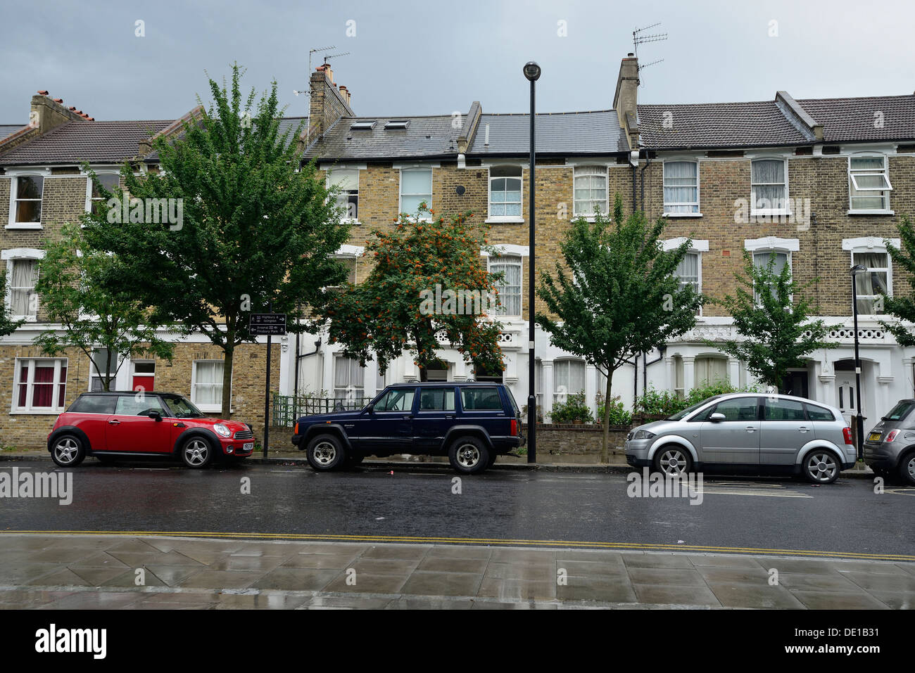 Typical street of London, with brick houses and cars parked along the ...