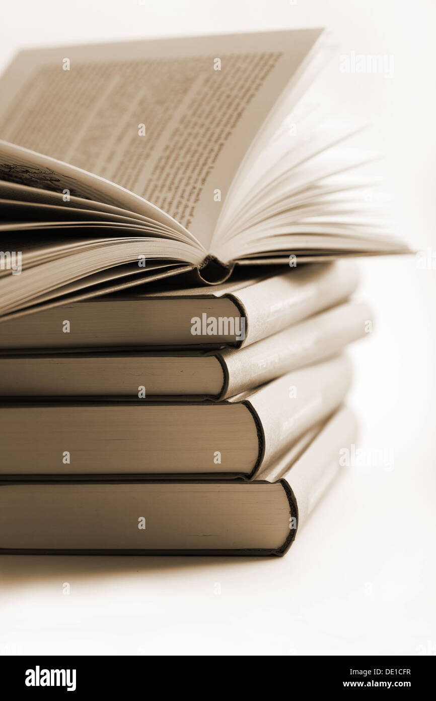 pile of books with one book open Stock Photo - Alamy