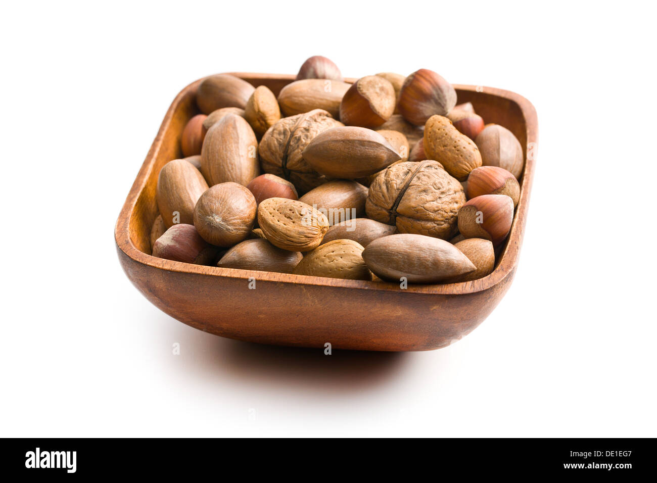 various unpeeled nuts in wooden bowl on white background Stock Photo ...