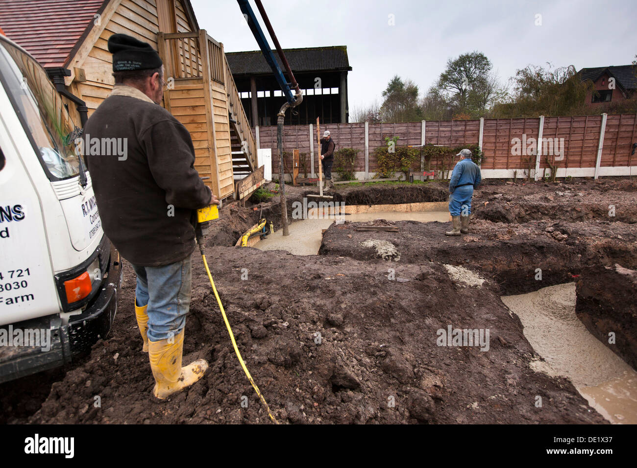 self building house, concrete foundations being poured and tamped level ...
