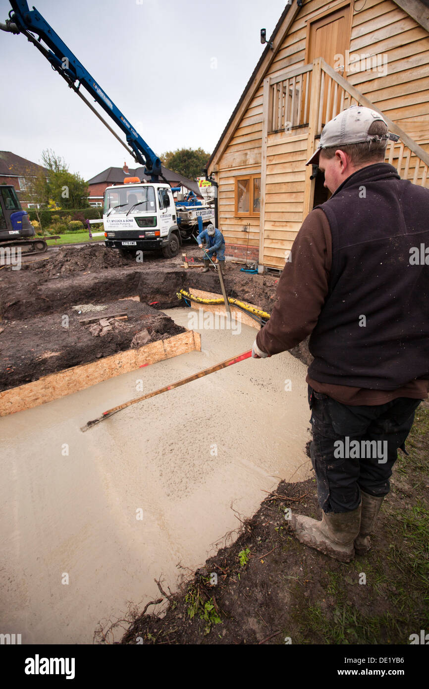 self building house, pumping concrete into foundations being tamped ...
