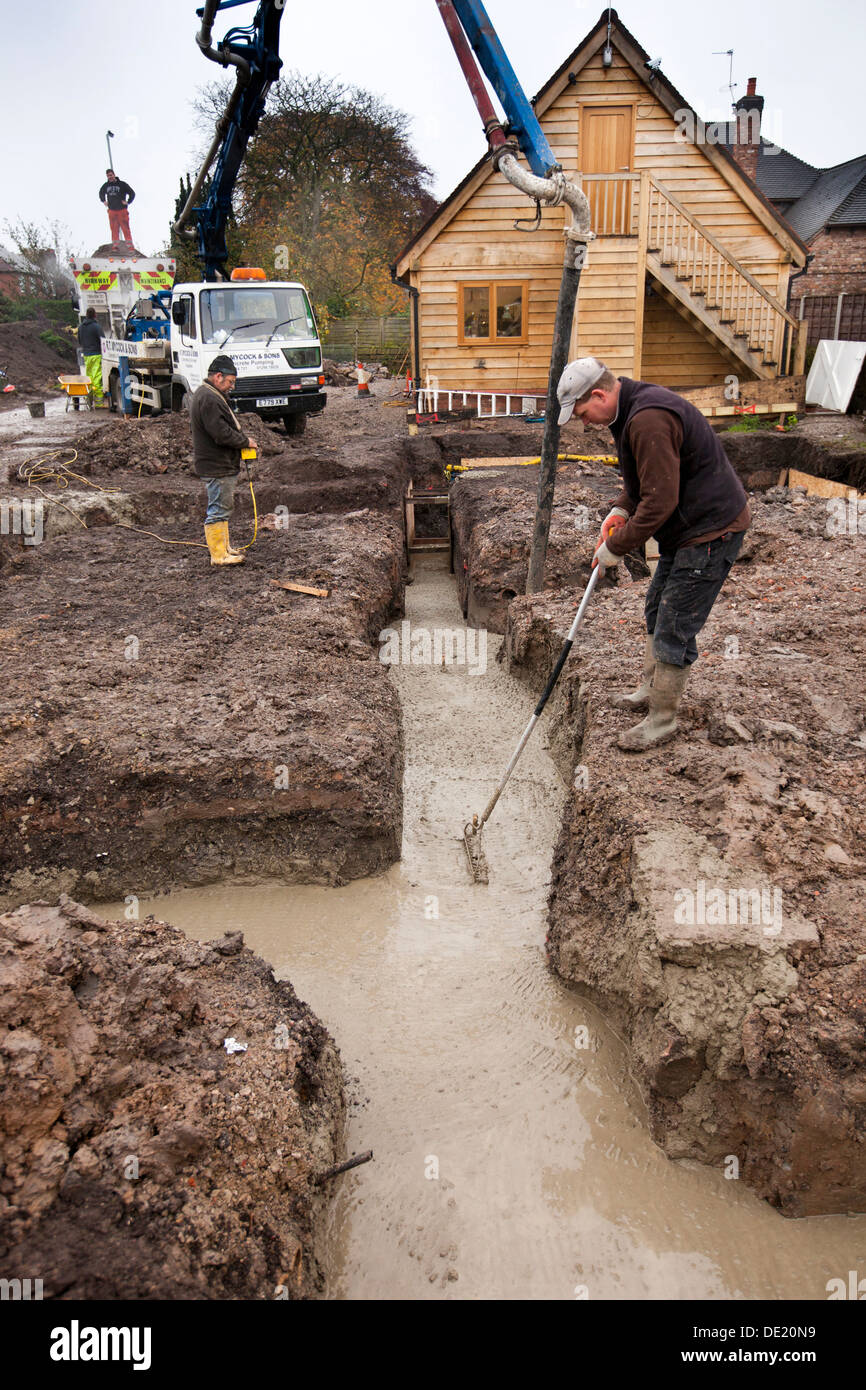 self building house, concrete foundations being poured and tamped level ...