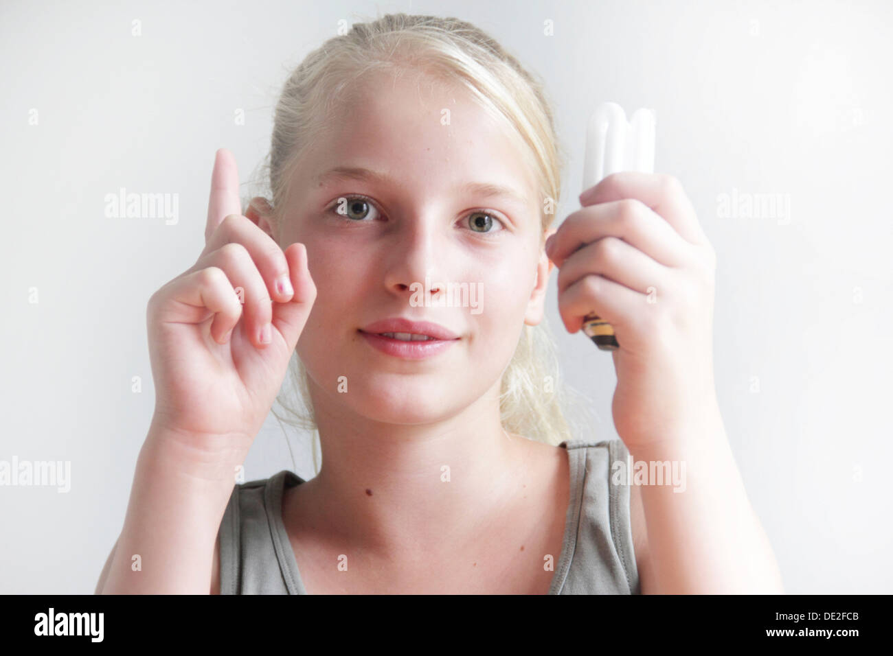 Girl holding an energy saving lamp in her hand and holding up her other ...
