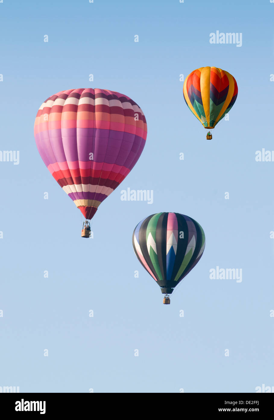 Three hot-air balloons floating against a blue sky Stock Photo - Alamy