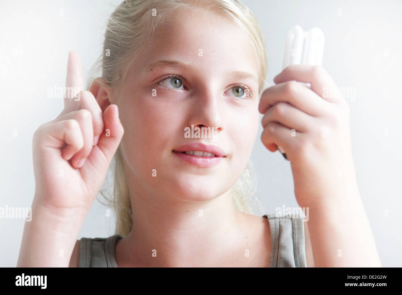 Girl holding an energy saving lamp in her hand and holding up her other ...