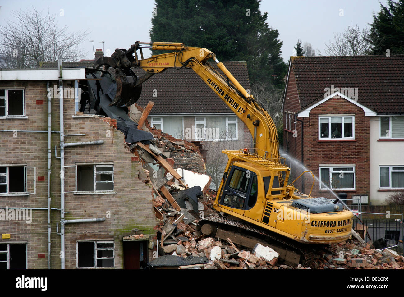 The Demolition of a Small block of Flats using an excavator. Water ...