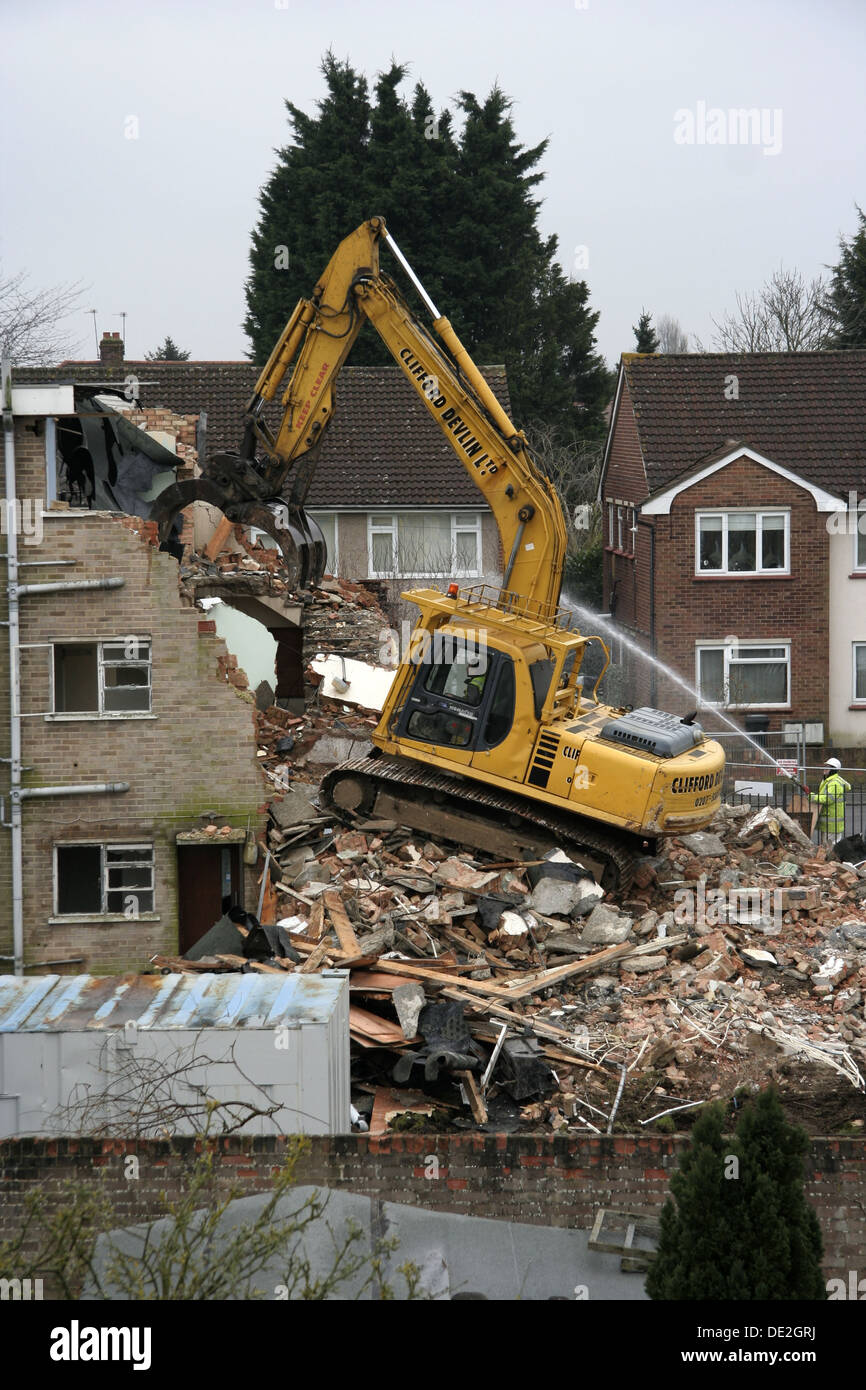 The Demolition of a Small block of Flats using an excavator. A man ...