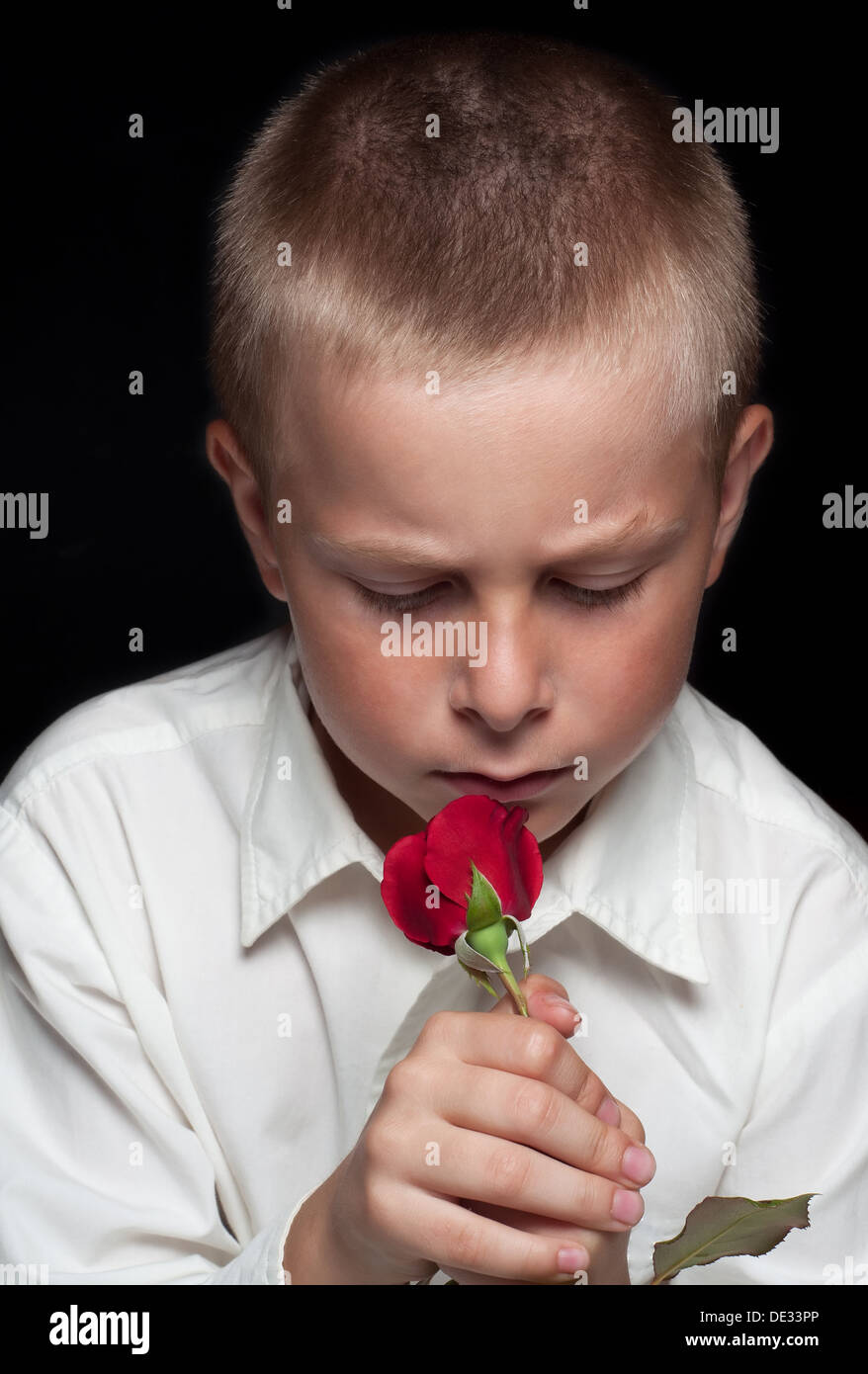 Boy with red rose isolated on black background Stock Photo - Alamy
