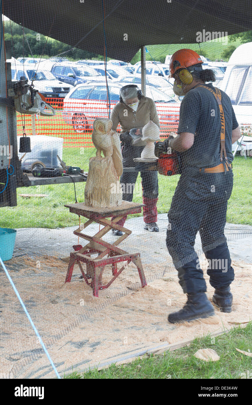 Wood carver using a chainsaw to carve a block of wood into an owl Stock ...