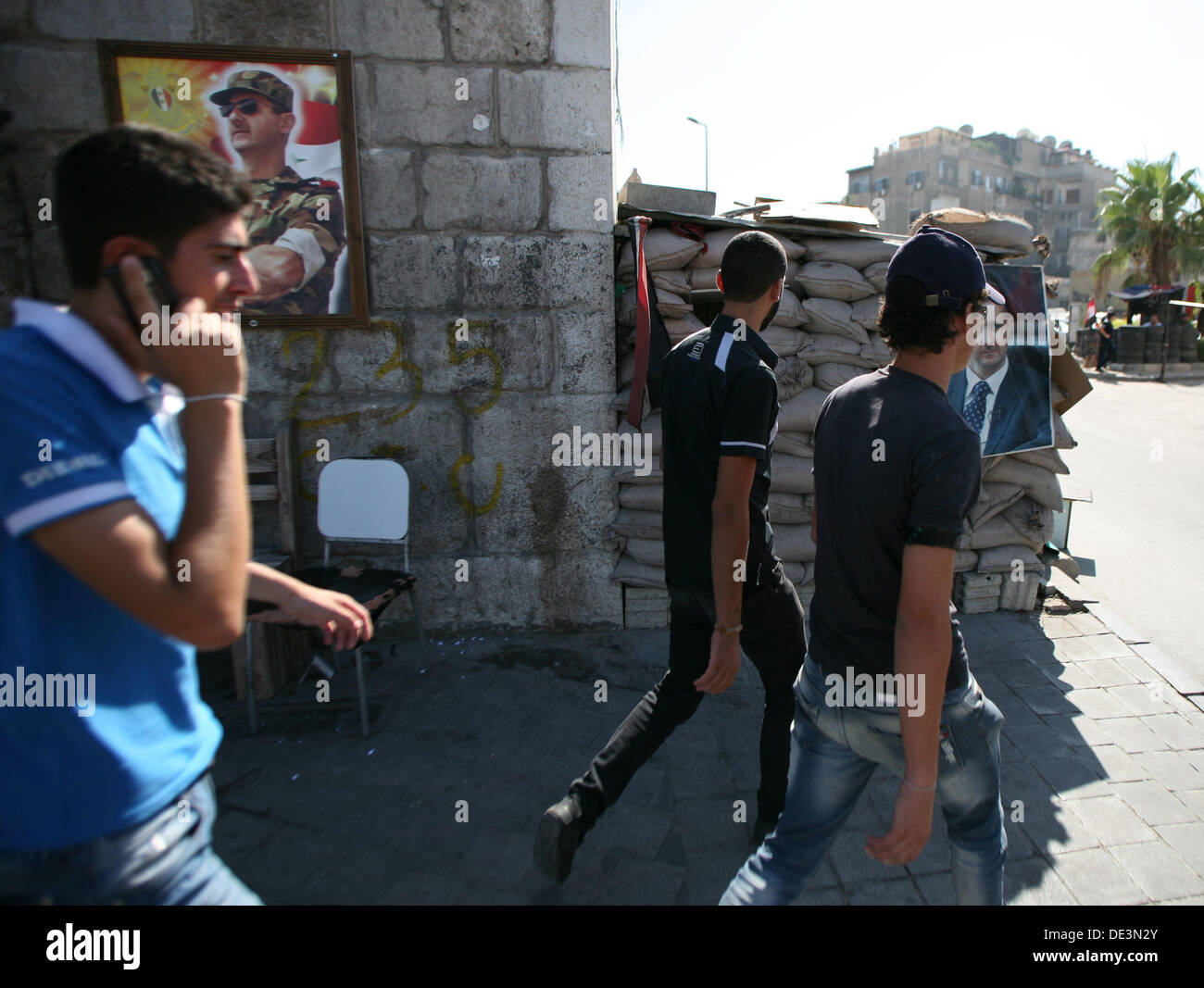 Young men approach a checkpoint of Syrian Arab Army adorned with ...