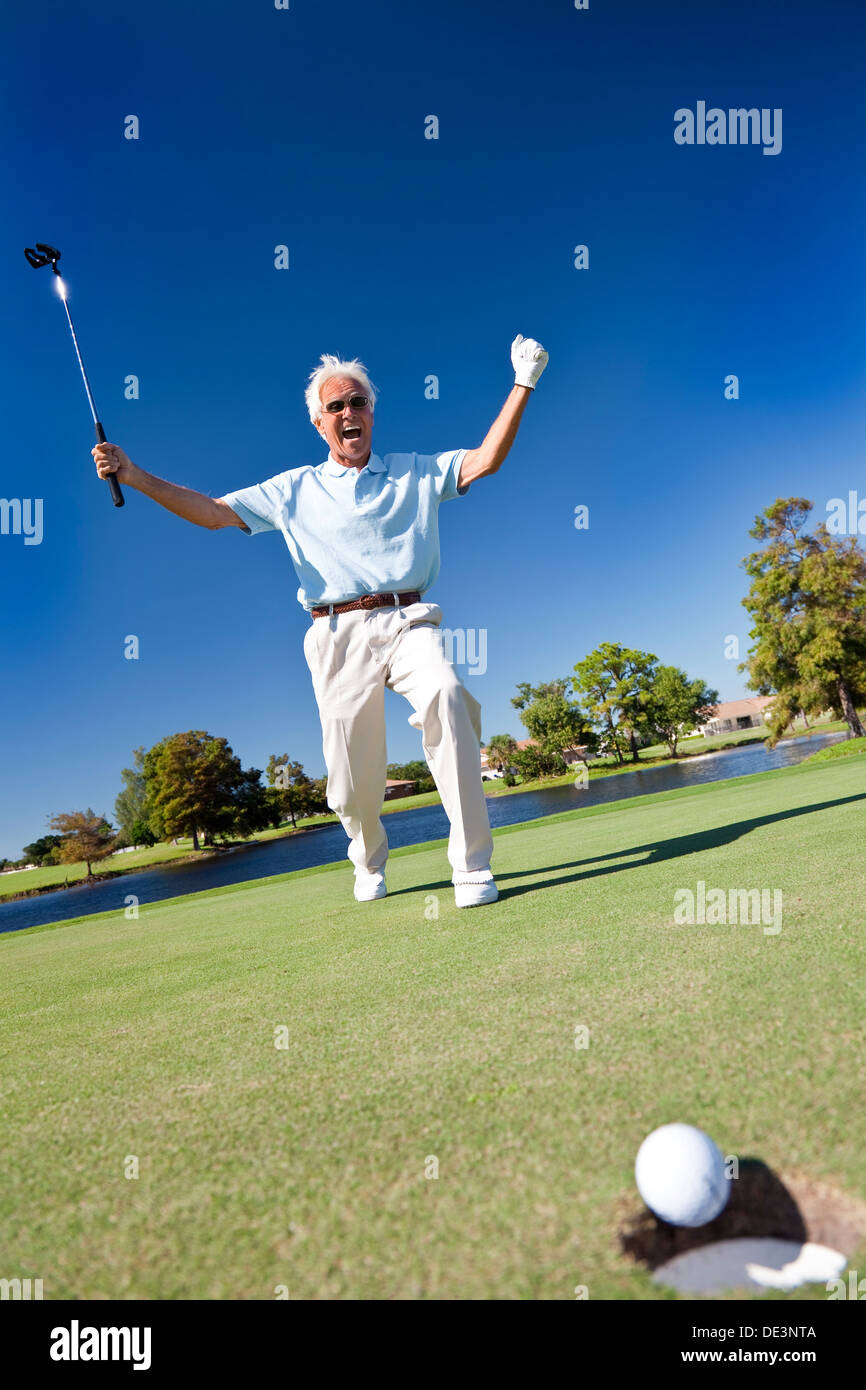 Happy senior man playing golf celebrating putting on a green Stock ...