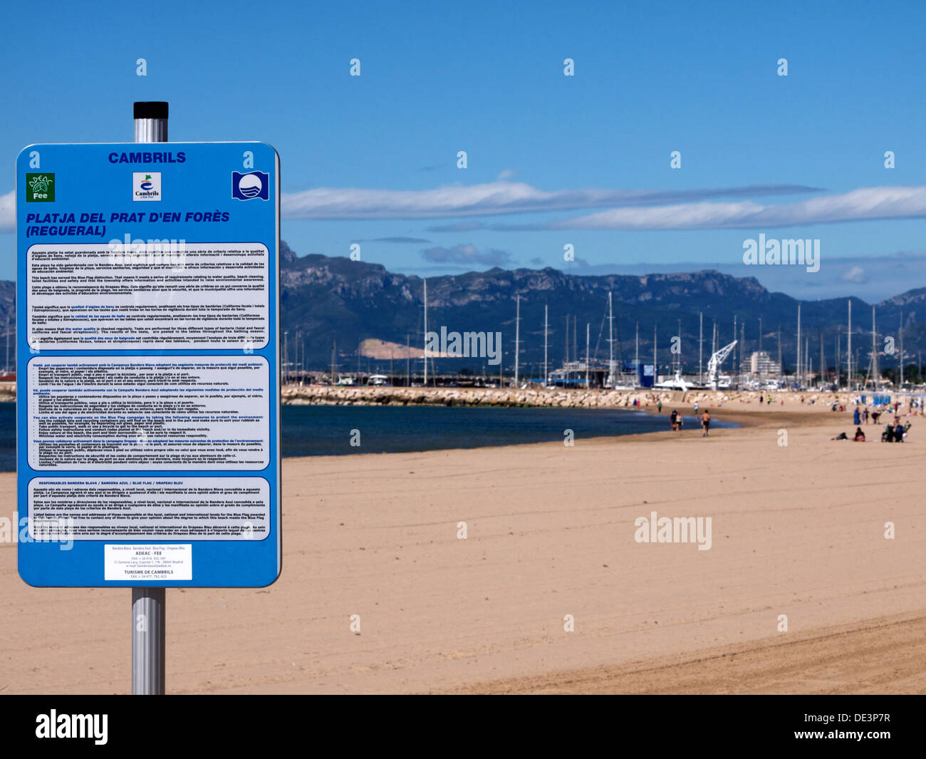 Beach information sign in spanish with the sand and water in the ...