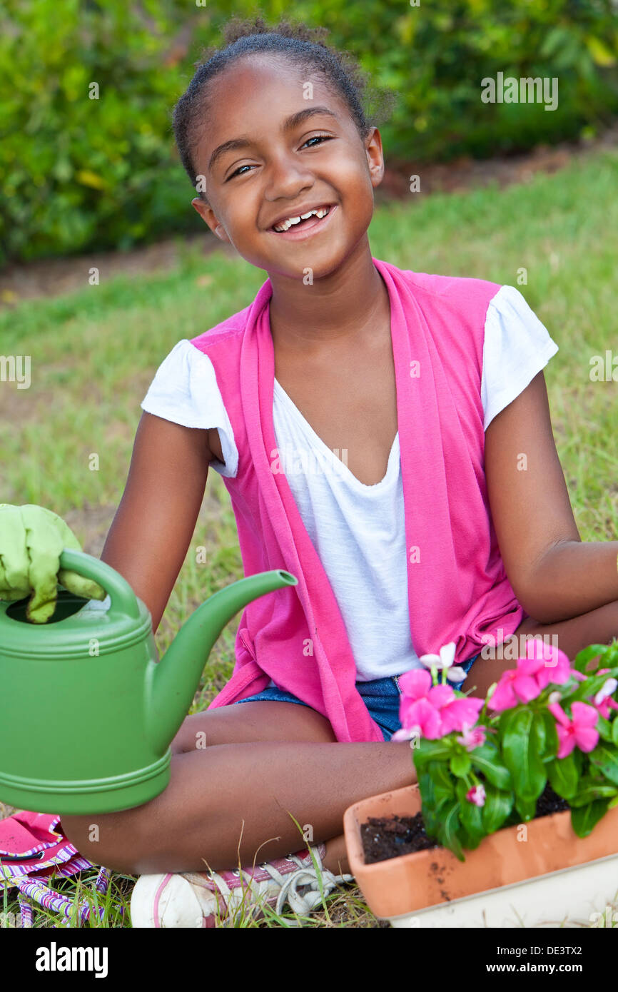 Happy African American girl child gardening planting flowers and ...