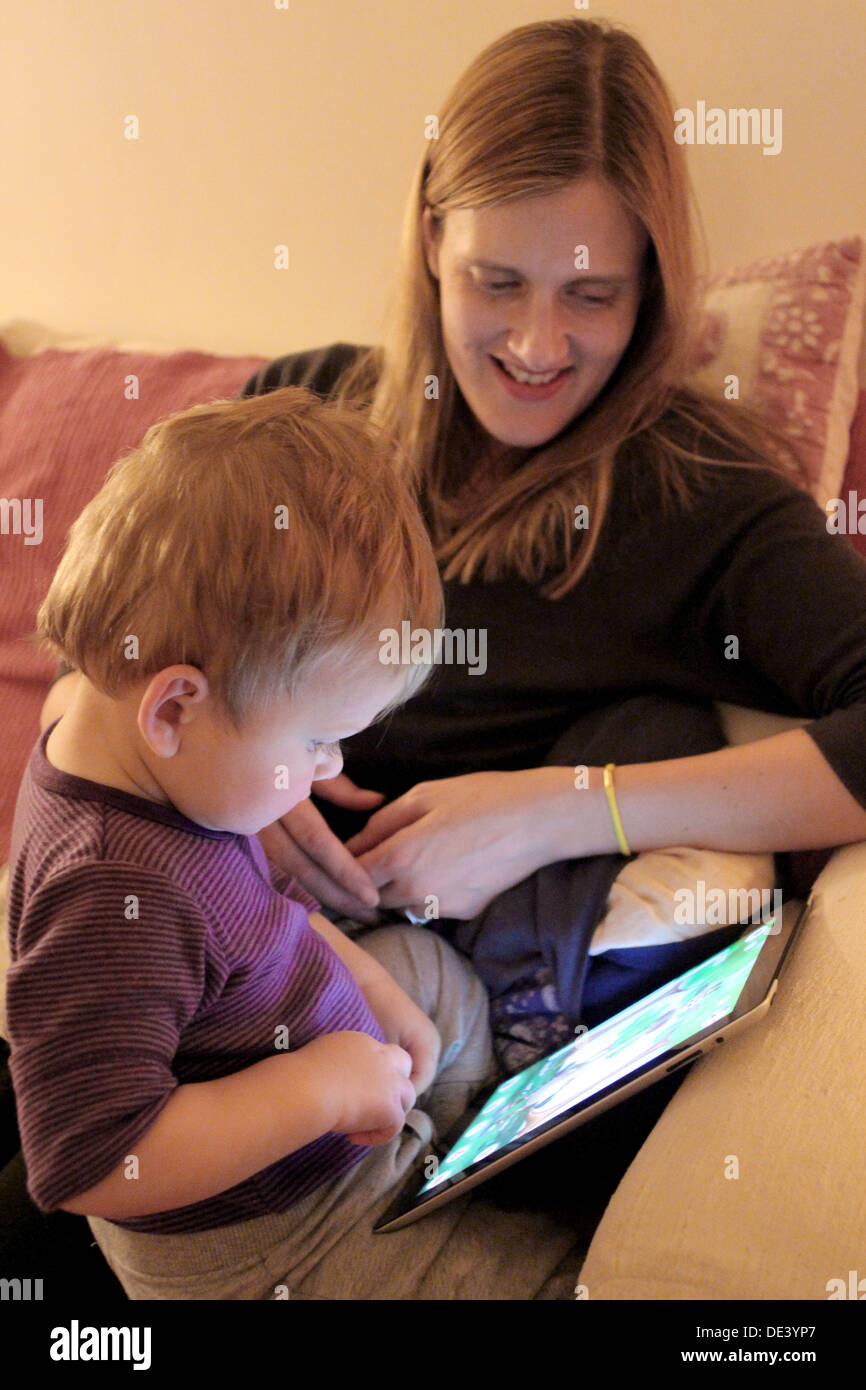 young boy playing on ipad with mother watching Stock Photo - Alamy