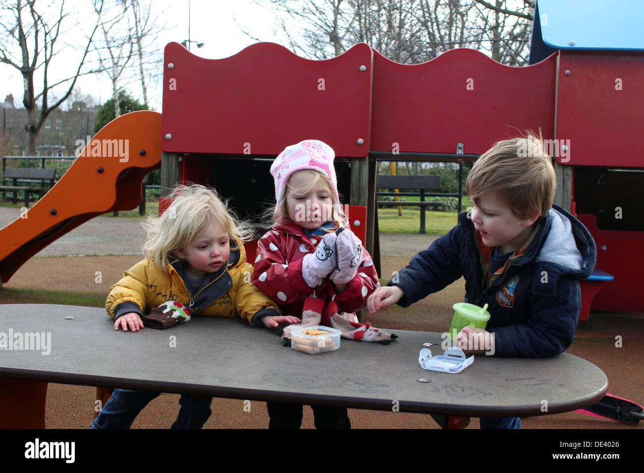 children eating picnic outdoors on table in playground climbing area ...