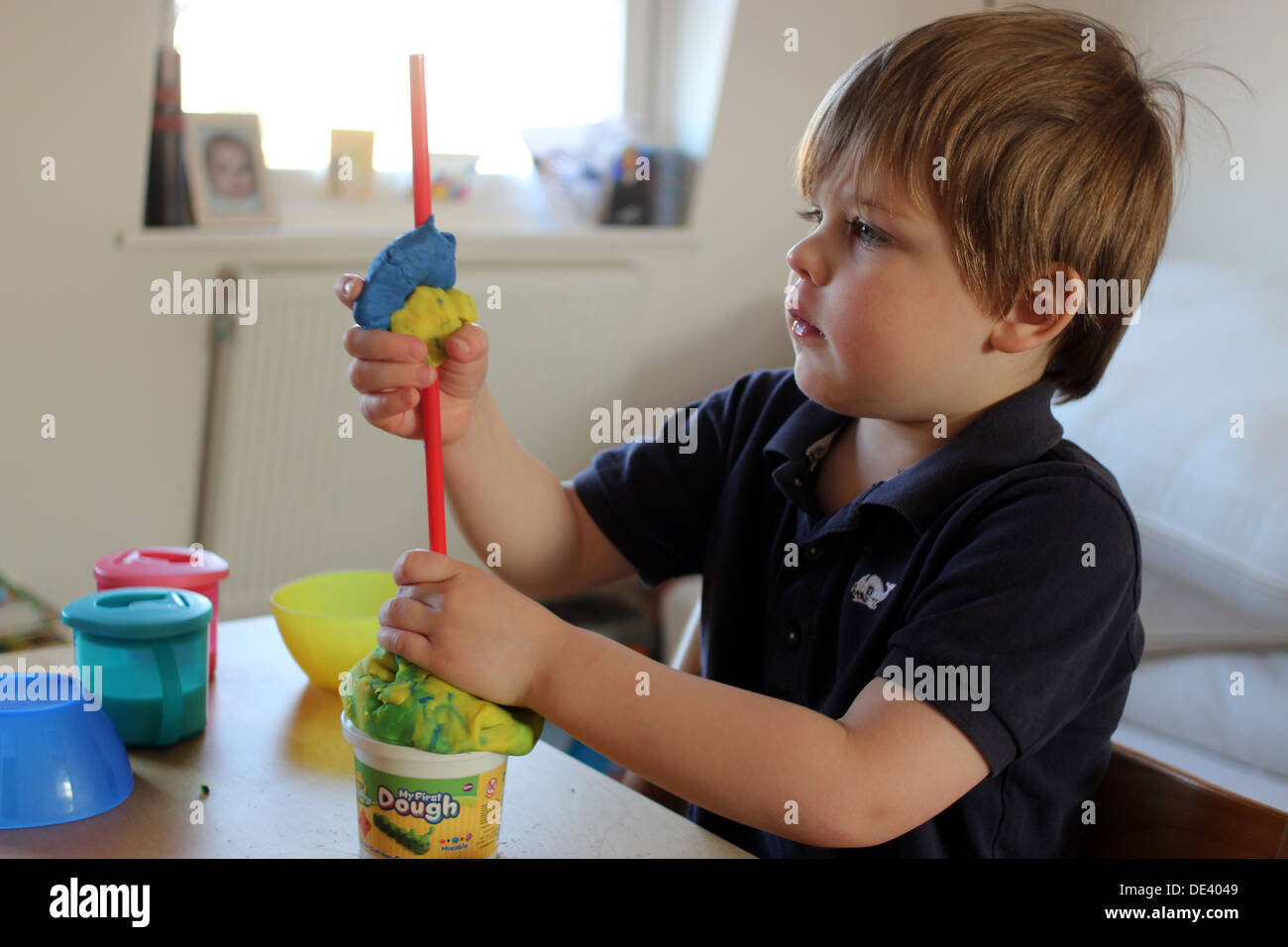 young boy playing with coloured play dough Stock Photo - Alamy