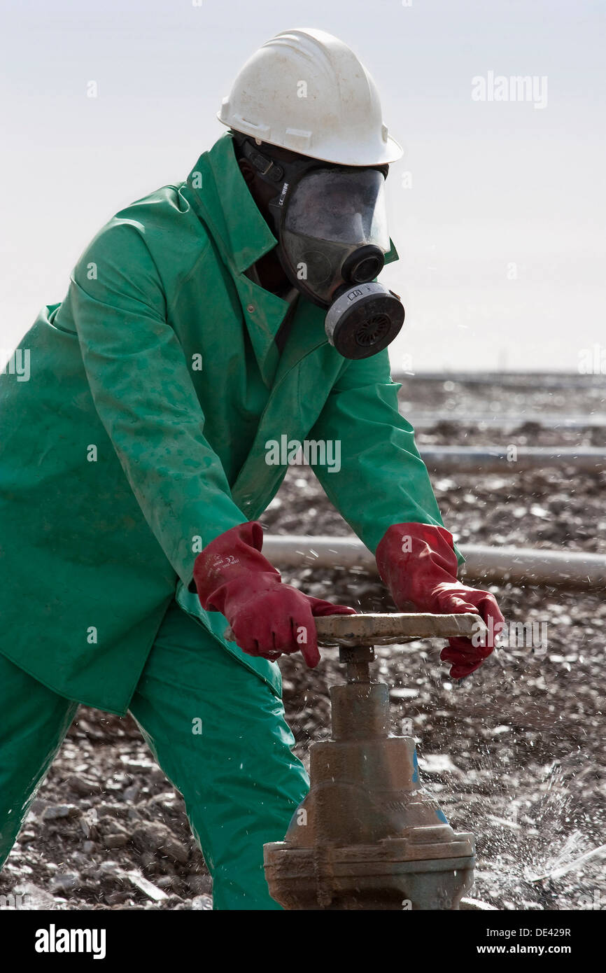 Operator adjusting valve on sprinkler system on dump heap leach pad ...