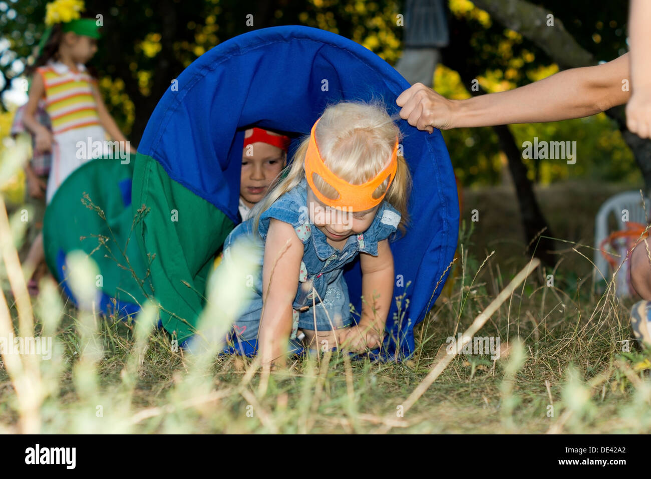 Children crawling through a fabric tube at a party being held up by ...