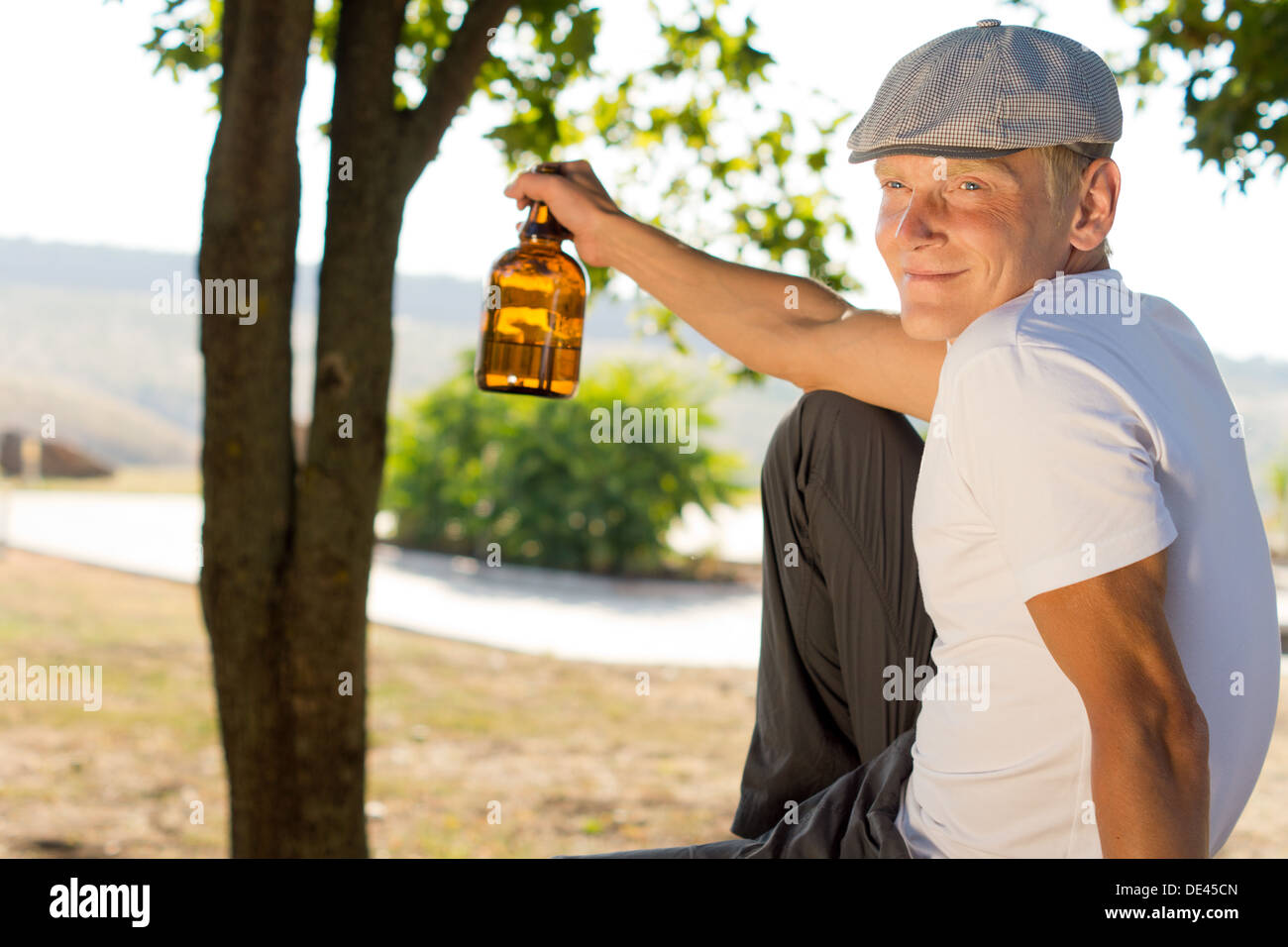 Happy drunk man with his bottle of booze or alcohol held in his hand ...