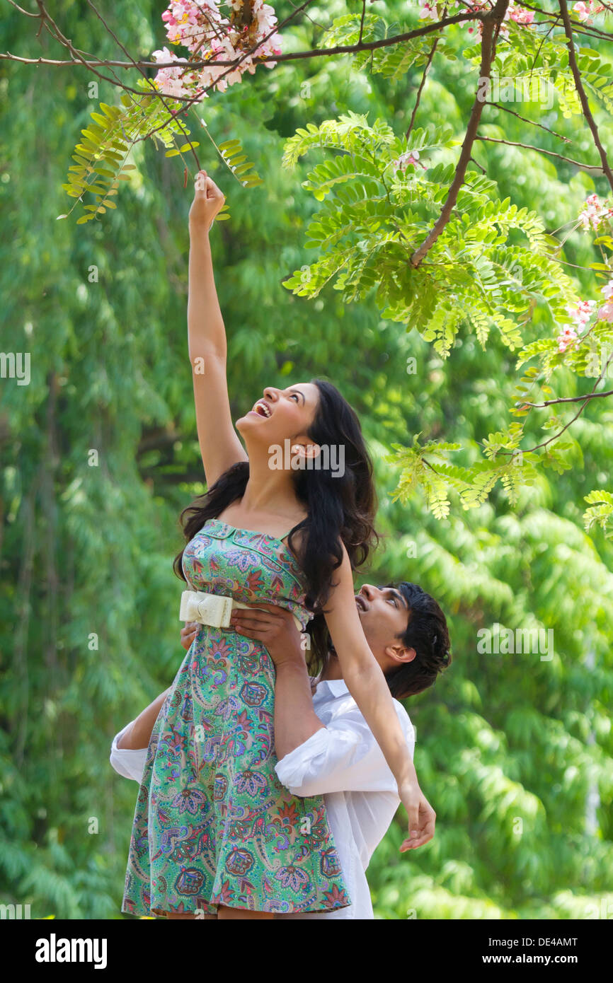 Man helping woman reach for branch of tree Stock Photo - Alamy