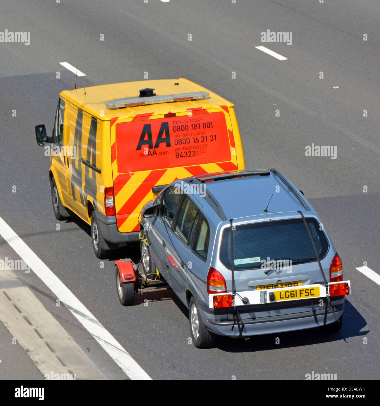 Aerial back view AA breakdown recovery van towing hatchback car on ... Aerial back view AA breakdown recovery van towing hatchback car on ...