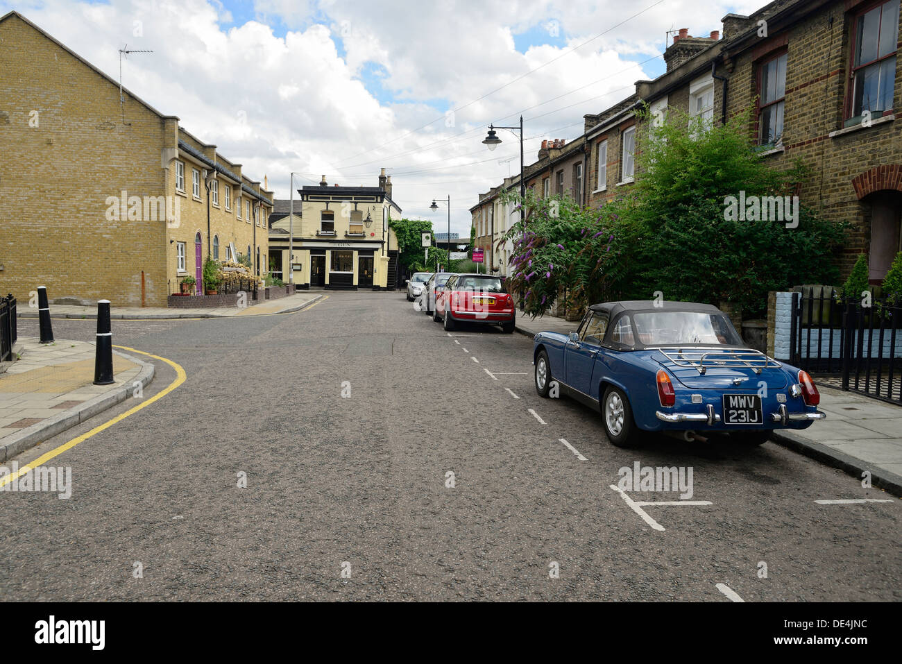 A typical London street with houses on both sides and cars parked in ...