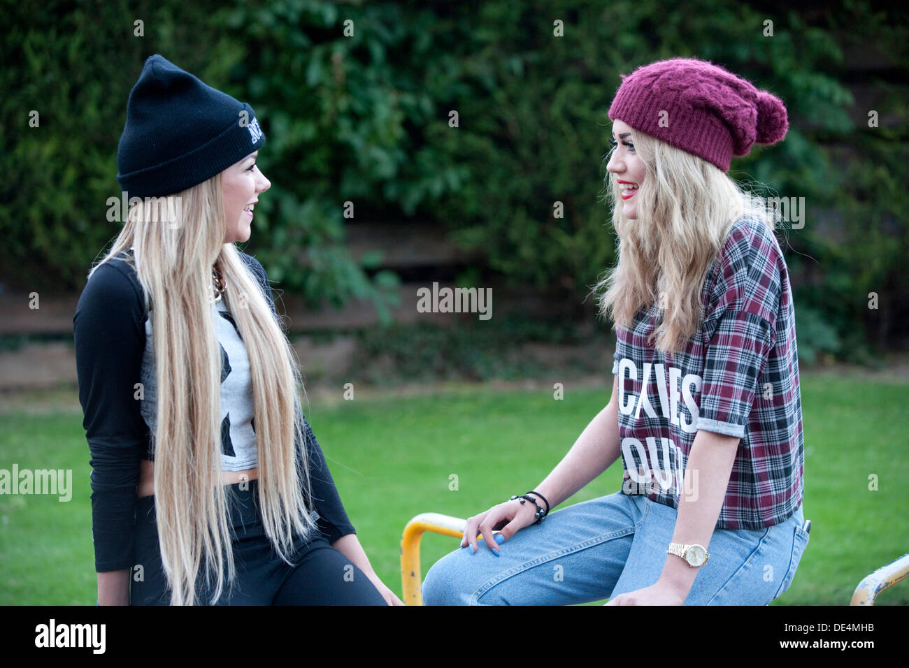 Two happy teenage girls sitting on a roundabout in a park Stock Photo ...