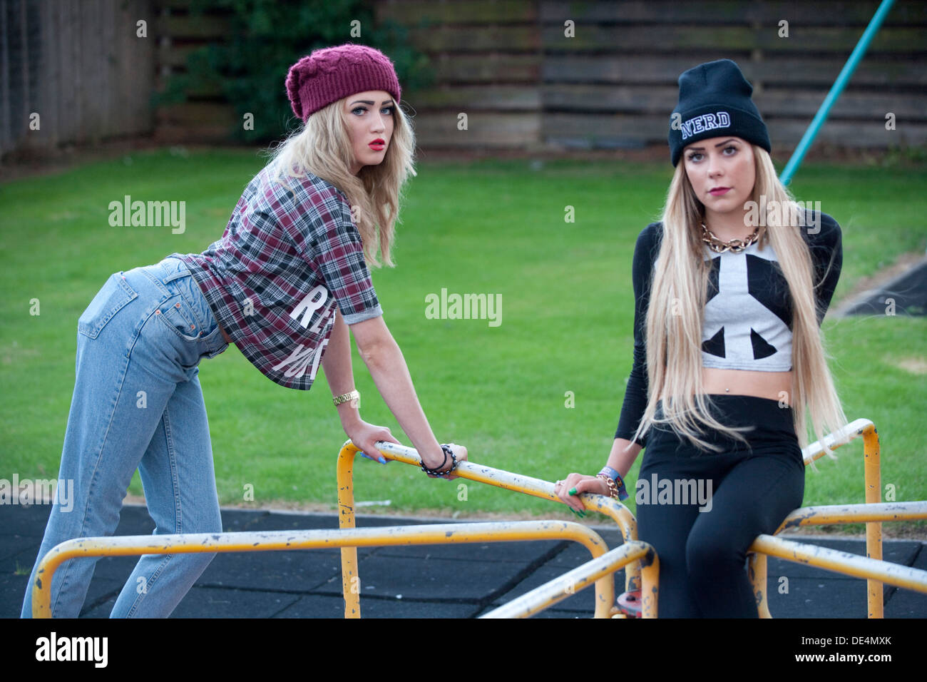 Two teenage girls sitting on a park roundabout Stock Photo - Alamy