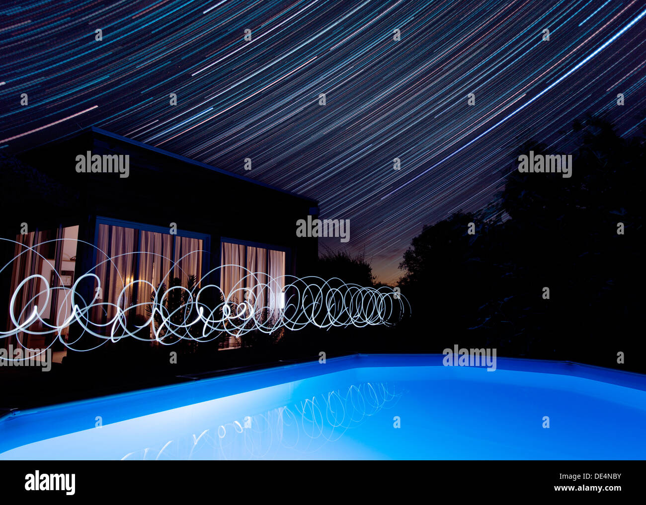 Starlight trails and floodlit swimming pool outside villa in late ...