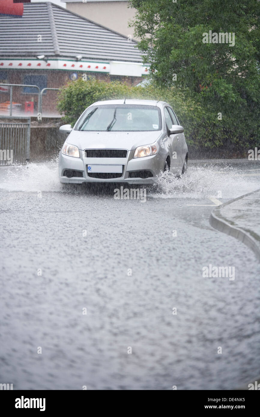 Silver car driving through flooded road Stock Photo - Alamy