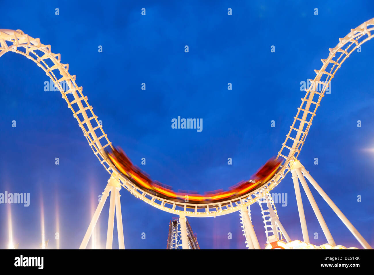 Riders on a roller coaster at an amusement park at night Stock Photo ...
