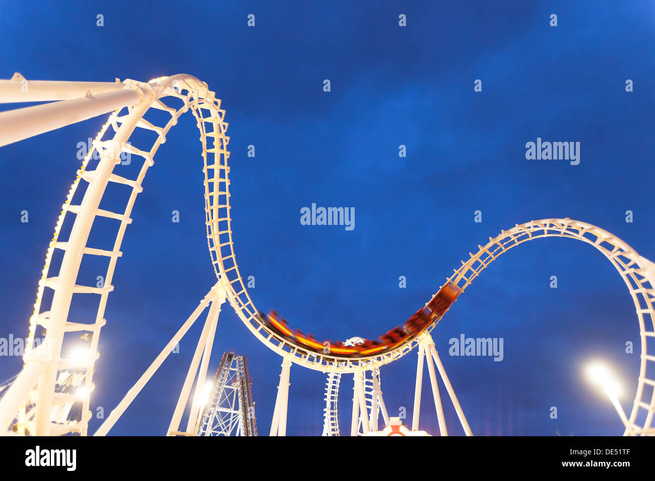 Riders on a roller coaster at an amusement park at night Stock Photo ...