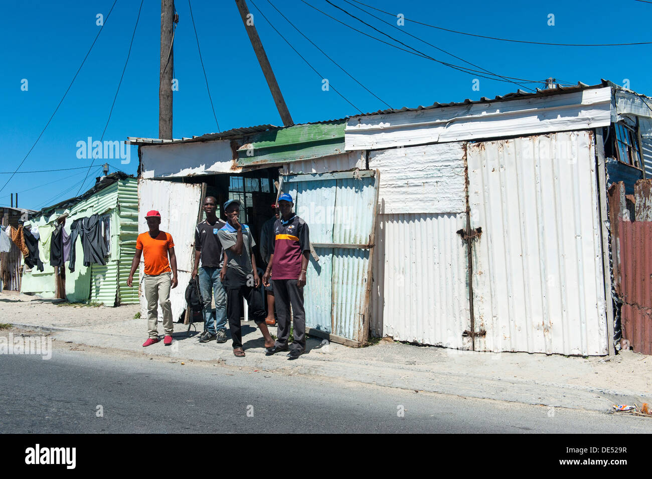 People standing in front of a tin shack in Khayelitsha, a partially ...