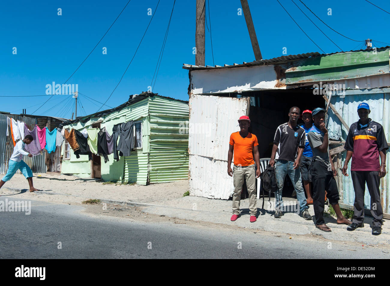 People standing in front of a tin shack in Khayelitsha, a partially ...