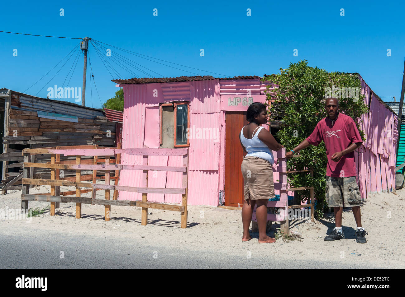 Man and woman talking in fron of a tin shack in Khayelitsha, a ...