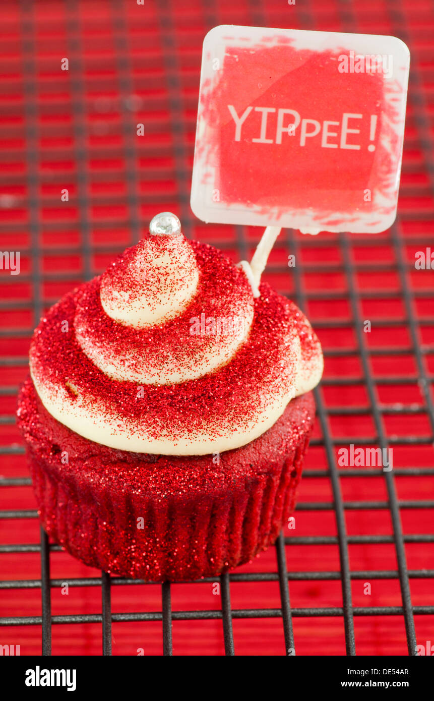 Red cupcake with a twirl on a grate with a note and the word: Yippee ...