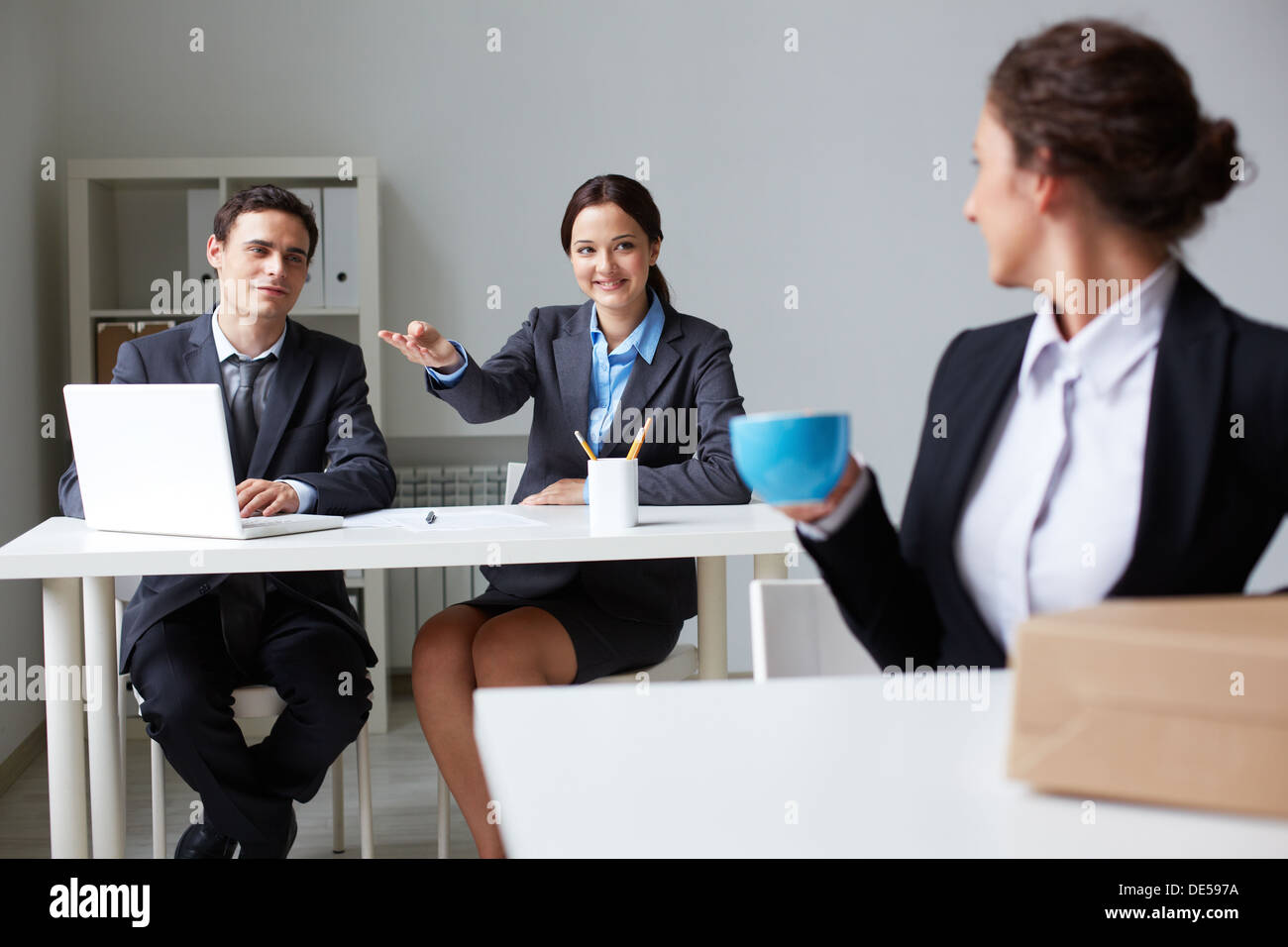Friendly businesswoman showing new colleague which place she may take ...