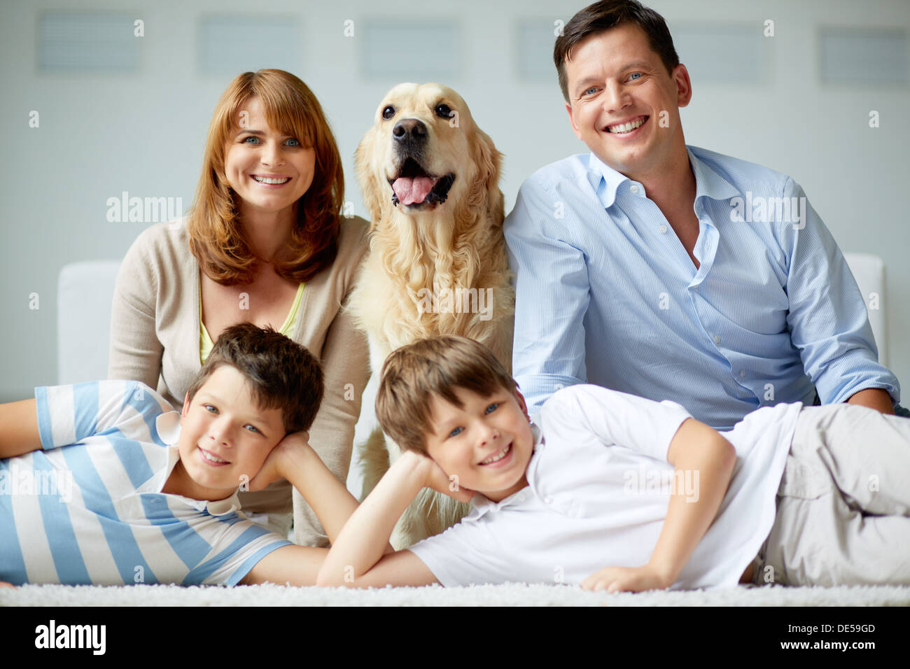 Portrait of happy family with fluffy Labrador having rest at home Stock ...