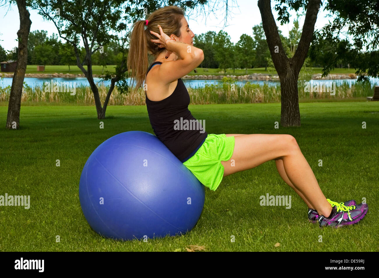 Young woman doing situps in a park, on a blue exercise ball Stock Photo ...