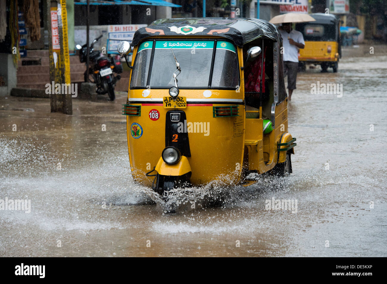 Indian auto rickshaws driving through wet streets in Puttaparthi ...