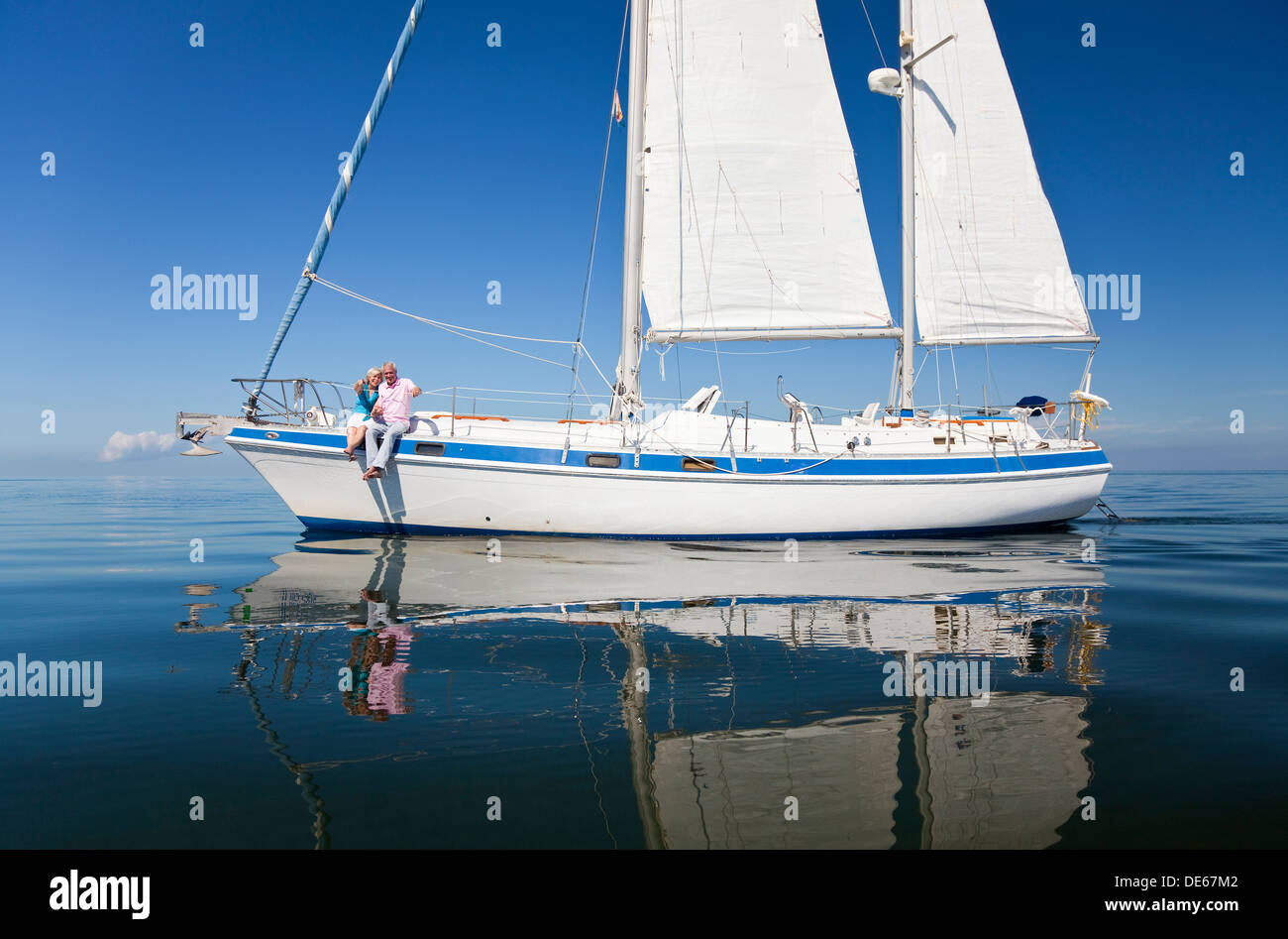 A happy senior couple having fun sitting on the deck of a sail boat on ...