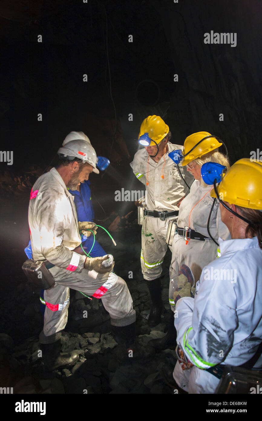 Visitors to an underground gold mine listen to the mine engineer and a ...