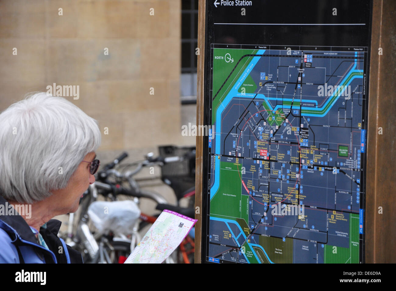 Elderly lady looks at map and sign Stock Photo - Alamy